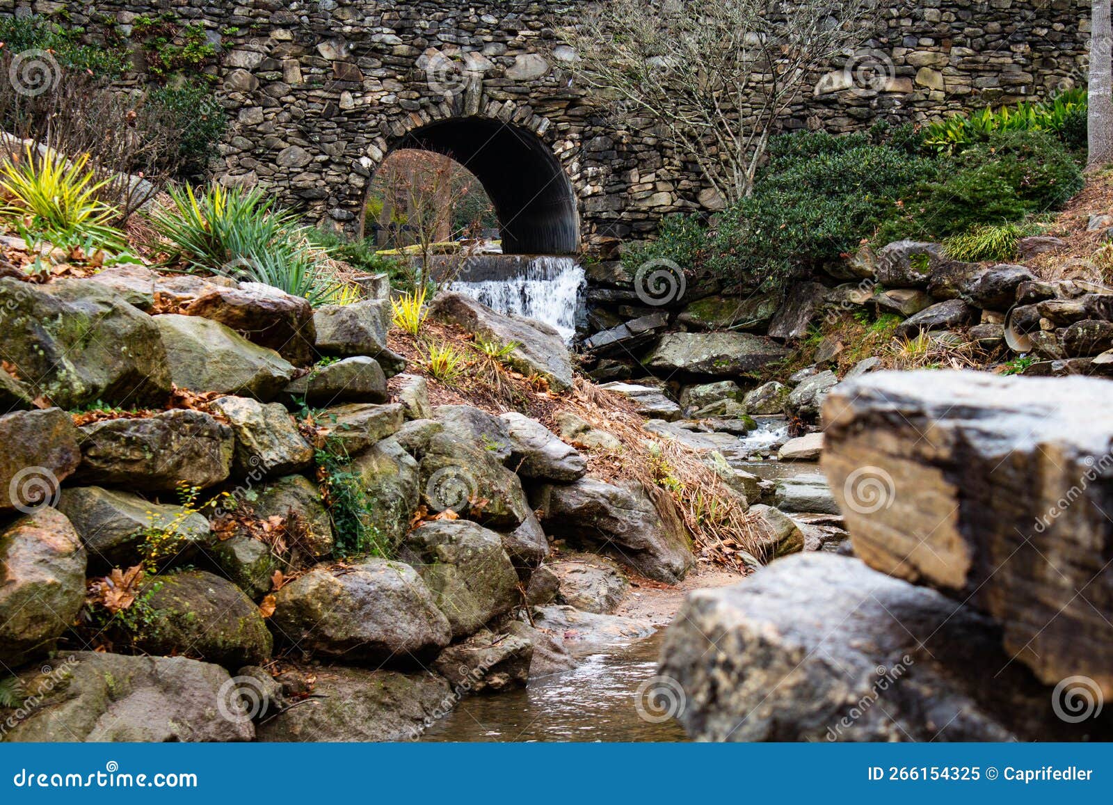 A Small Waterfall with a Stream Next To a Stone Wall Stock Image ...