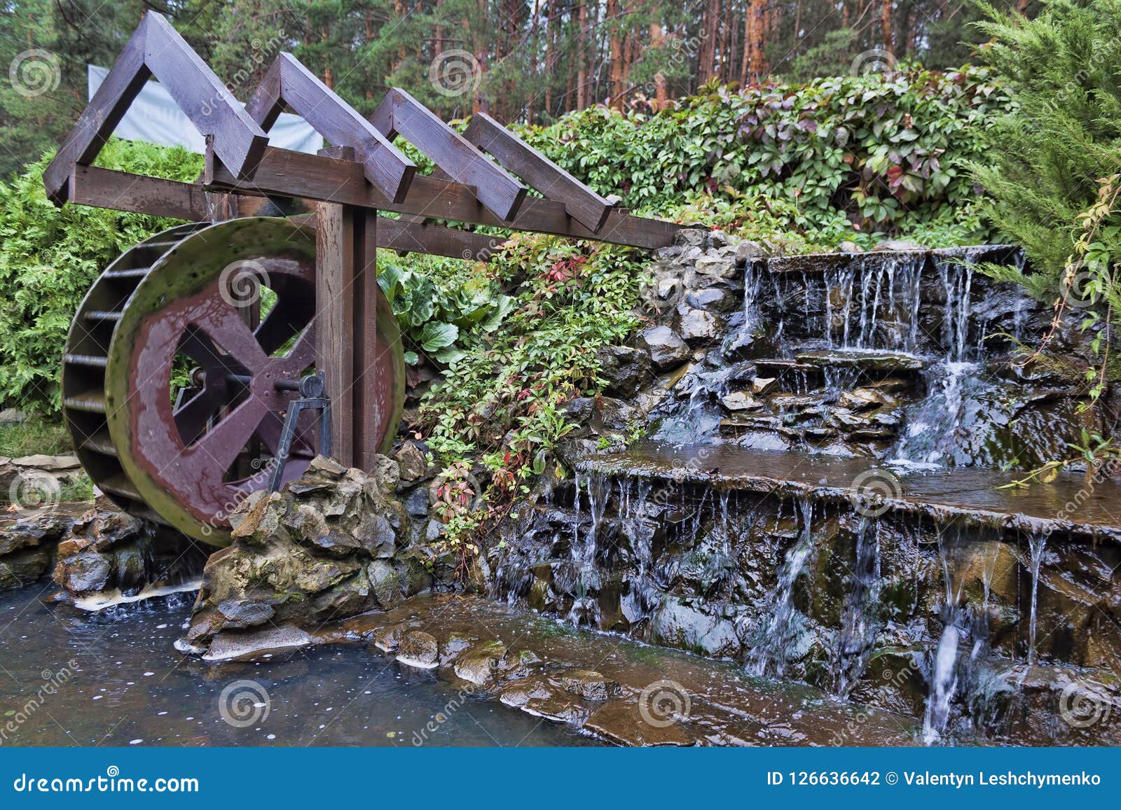 A Small Watermill Next To a Small Artificial Waterfall Stock Photo ...