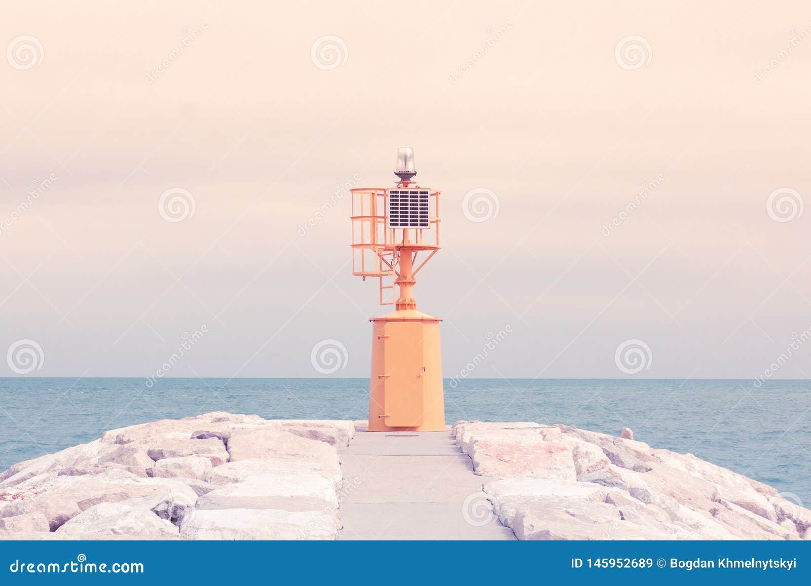 Small Yellow Lighthouse at the End of the Pier Against the Blue Sea ...