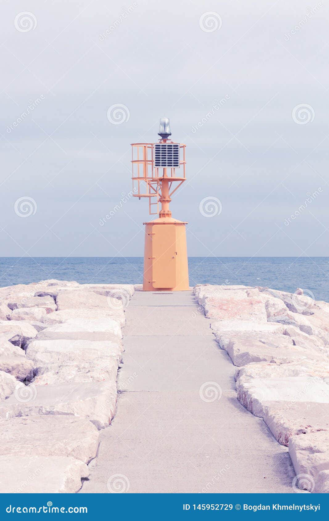 Small Yellow Lighthouse at the End of the Pier Against the Blue Sea ...