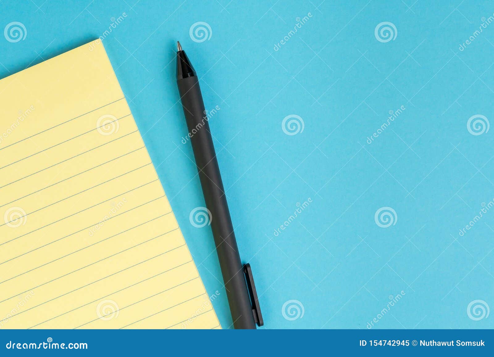 Small Yellow Paper Notepad with Blank Page, Pen on Solid Blue ...