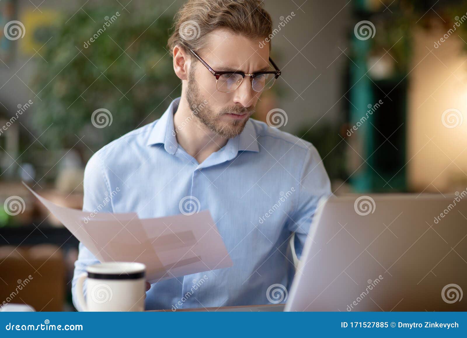 Smart Man with Drafts in His Hand Working at Laptop. Stock Image ...