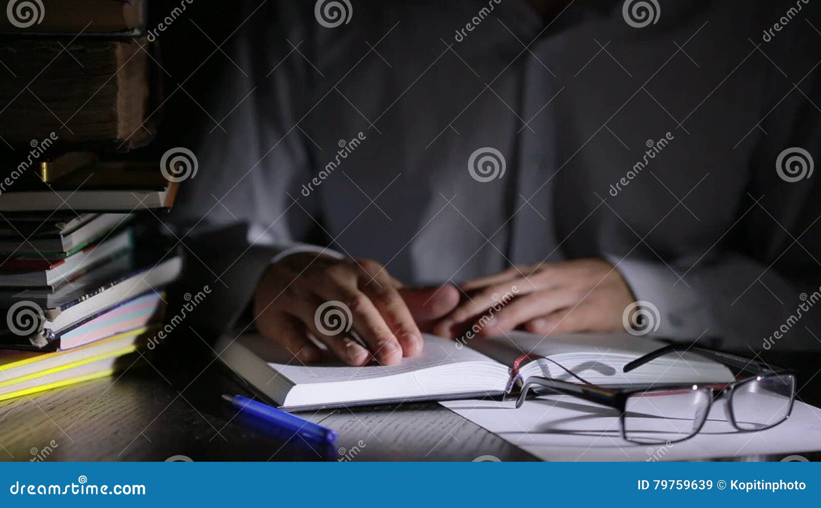 Smart Man Studying Late at Night, he is Sitting at Desk and Reading ...