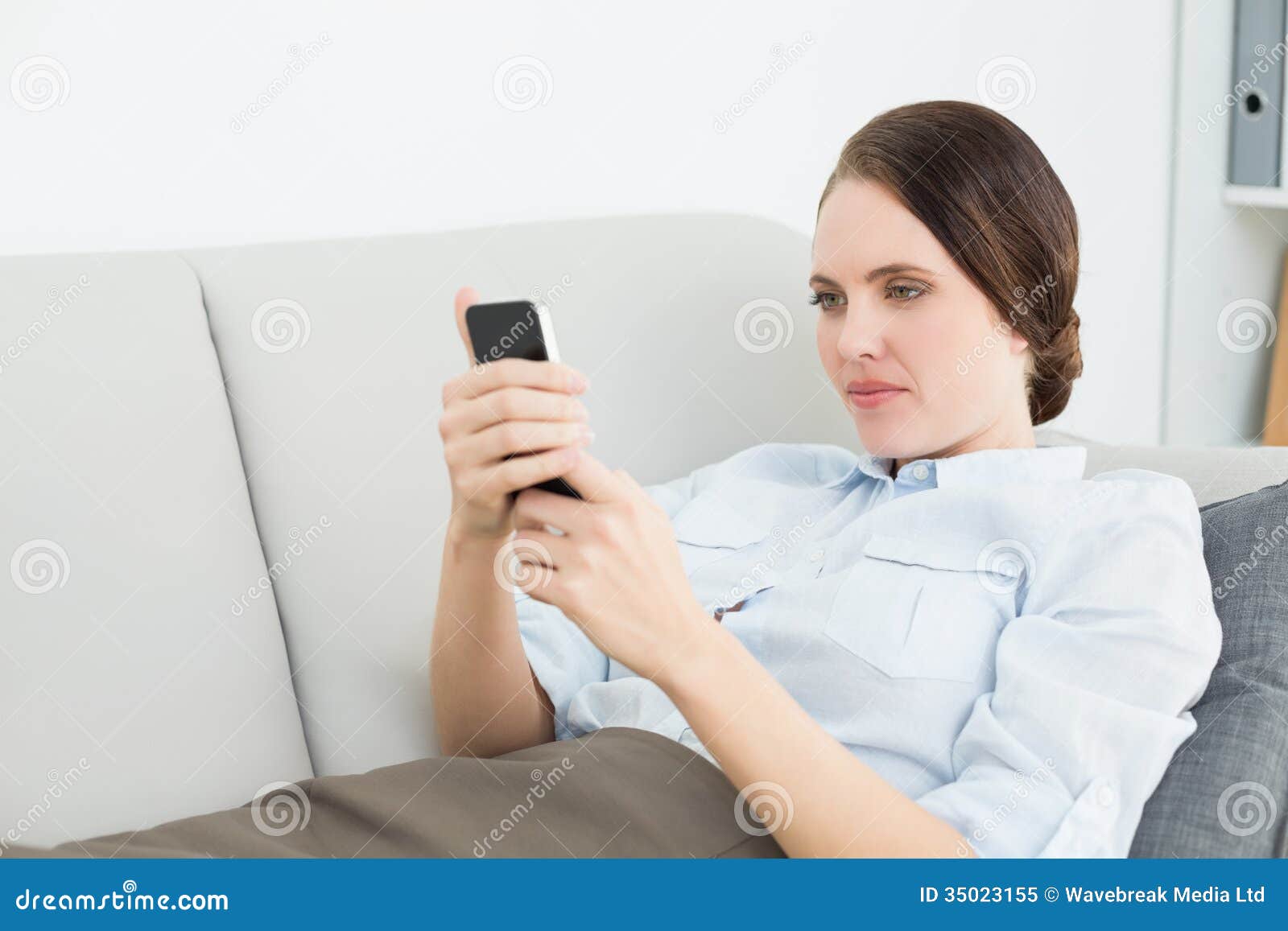 Smartly Dressed Woman Reading Text Message while Lying on Sofa Stock ...