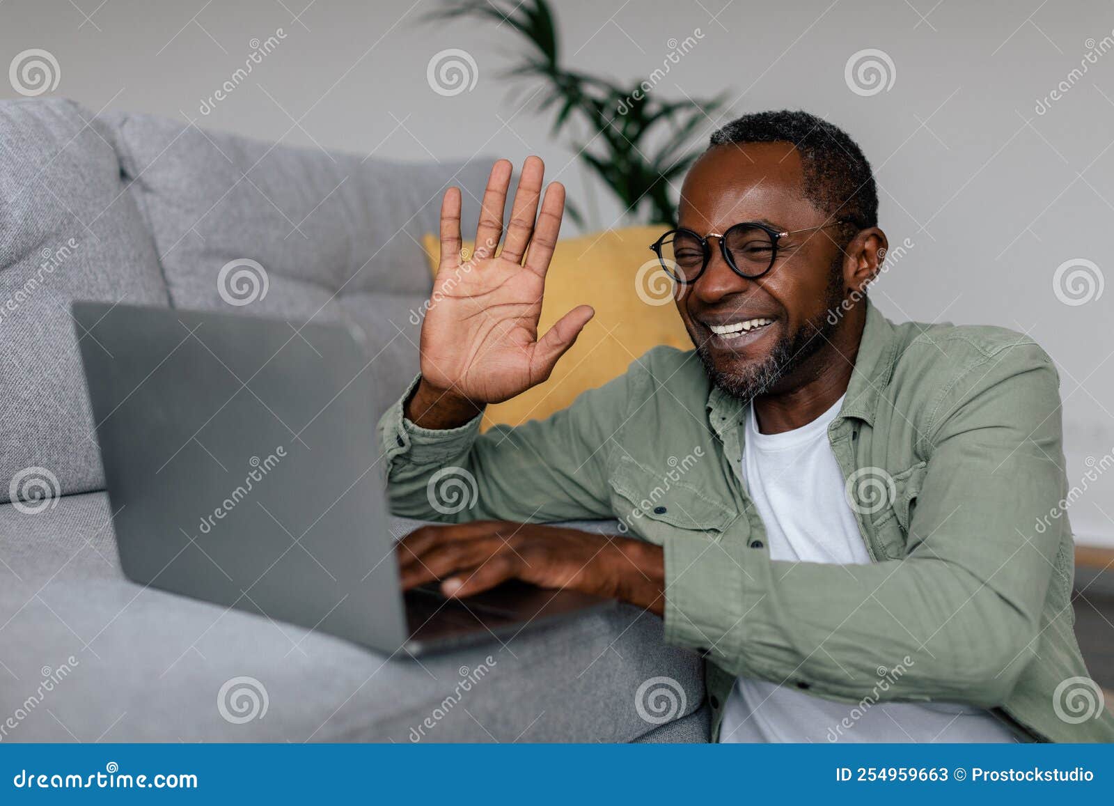 Smiling Adult African American Man In Glasses Waving Hand Gesture At