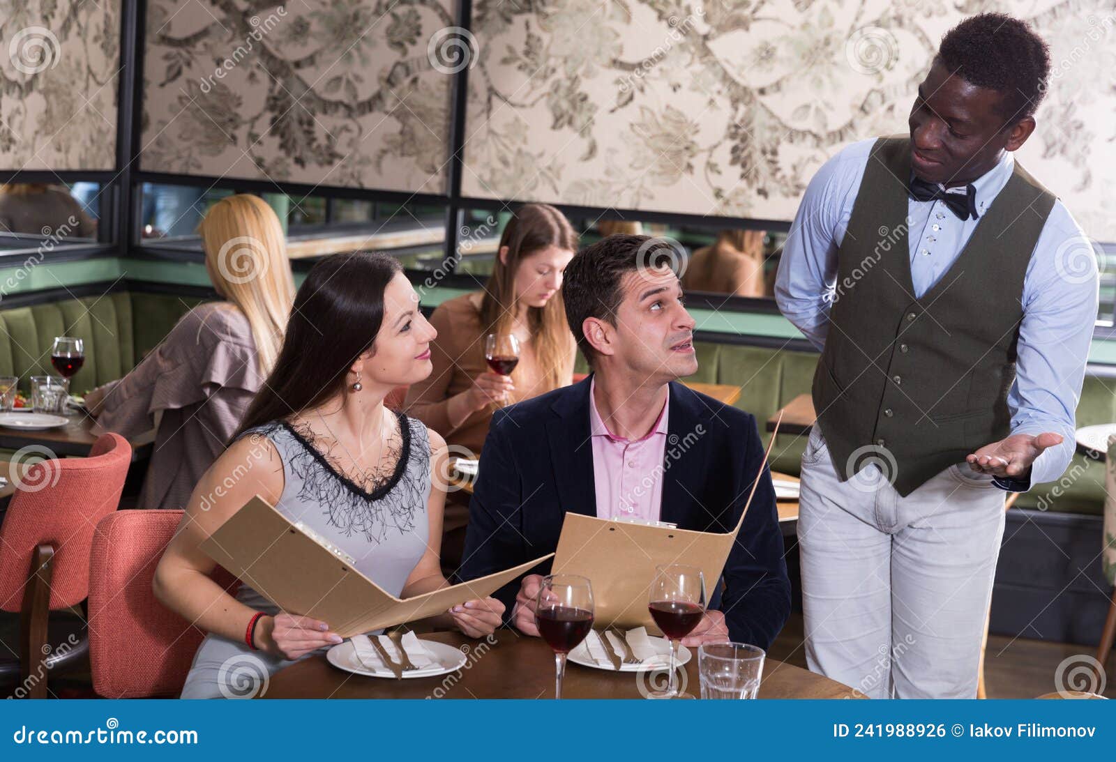 African American Waiter Recommending Dishes From Restaurant Menu Stock