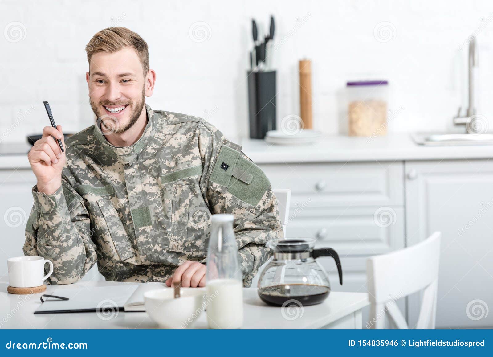 Smiling Army Soldier Sitting at Kitchen Table with Pen and Notebook ...
