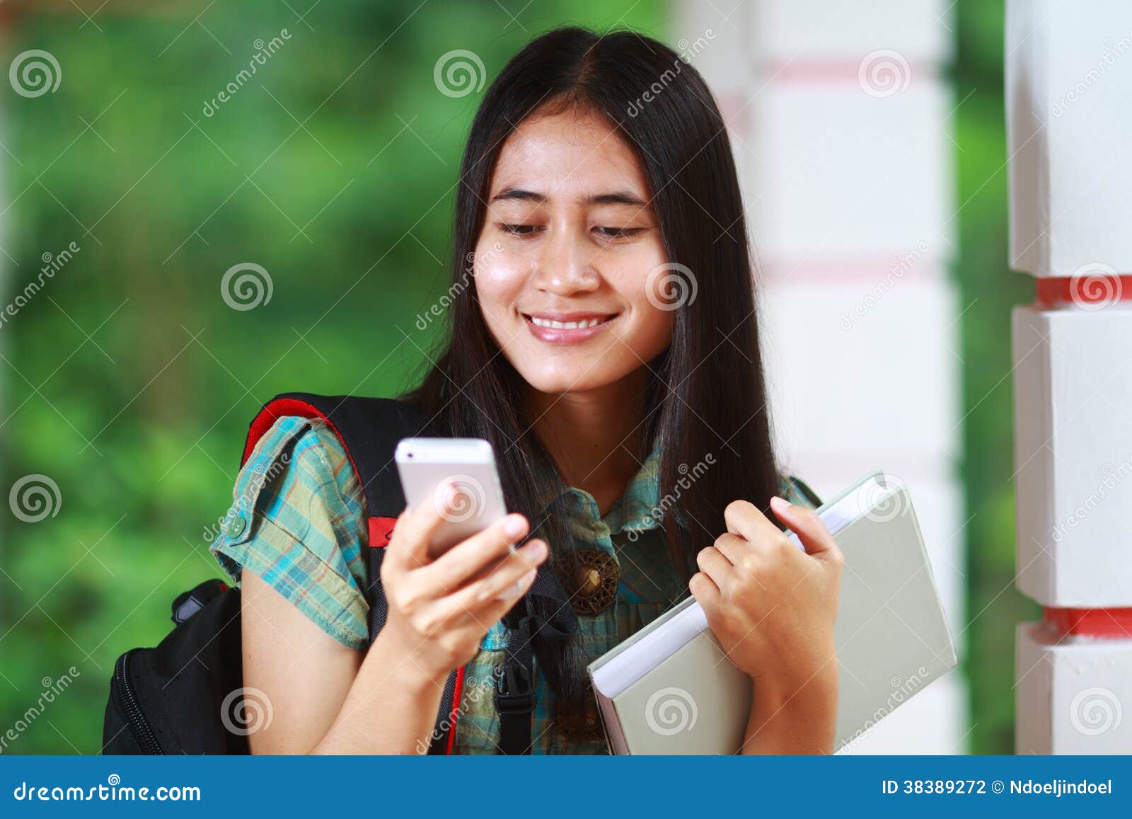 Smiling Asian Student Holding Book and Reading Text Message Stock Photo ...