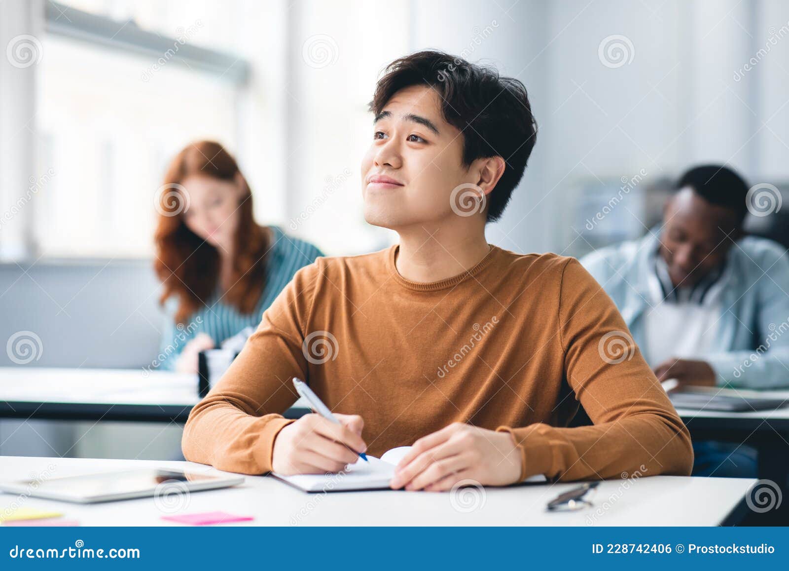 Smiling Asian Student Sitting at Desk in Classroom Looking Away Stock ...