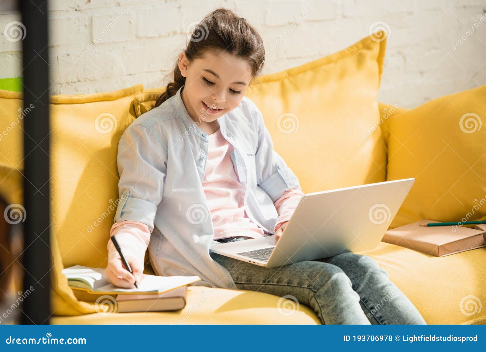 Attentive Kid Writing in Copy Book and Using Laptop while Sitting on ...