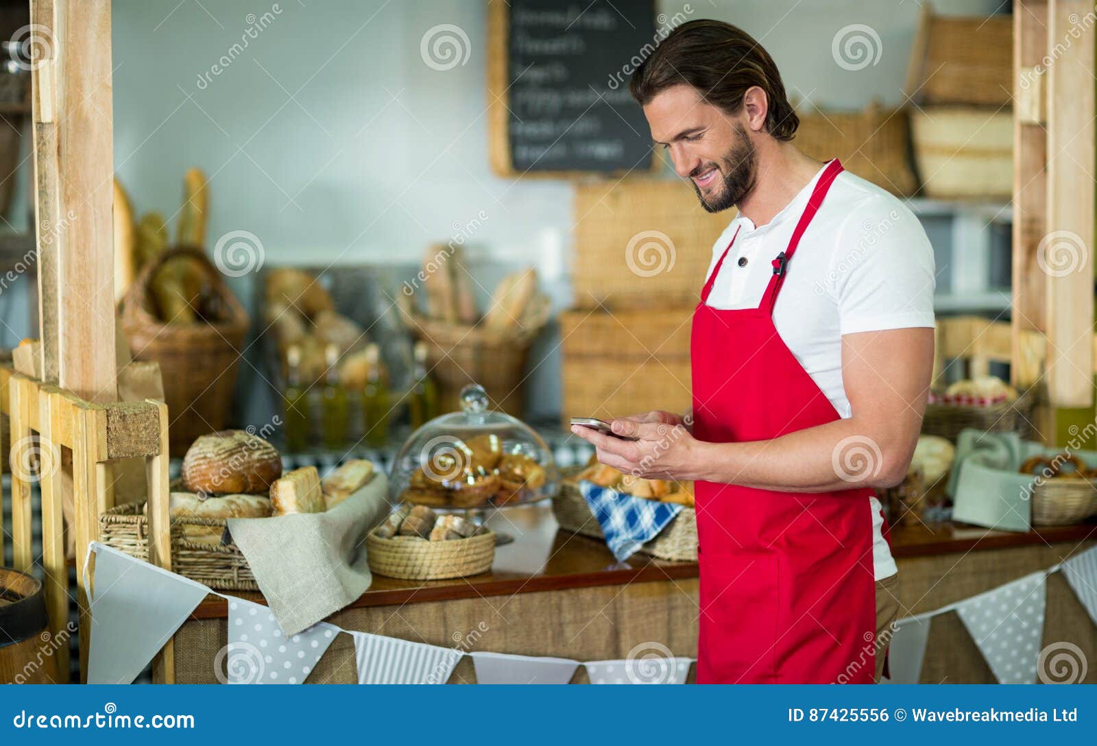 Smiling Bakery Staff Using Mobile Phone at Counter Stock Photo - Image ...