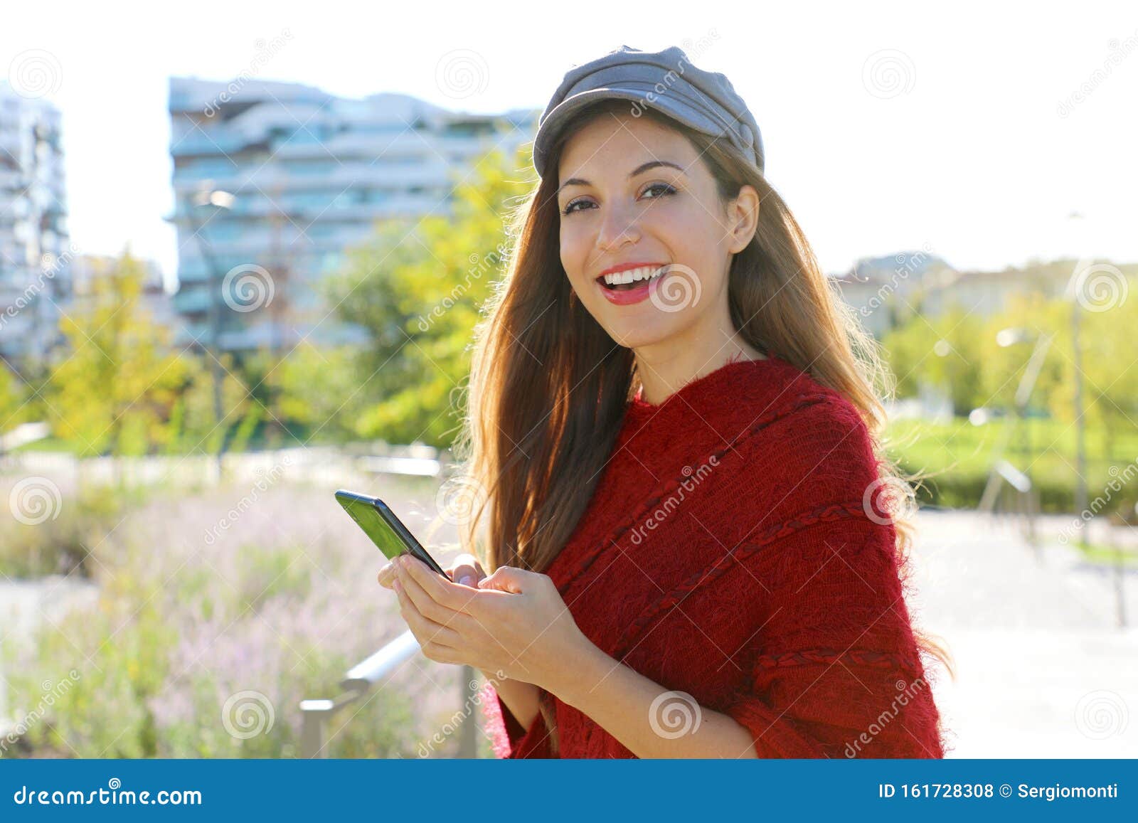 Smiling Beautiful Fashion Woman Using Smart Phone Looks at Camera ... Smiling Beautiful Fashion Woman Using Smart Phone Looks at Camera ...