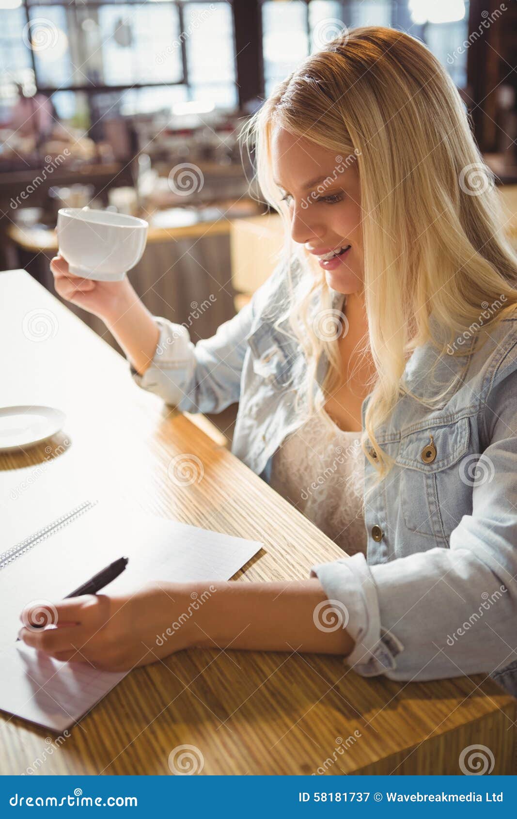 Smiling Blonde Drinking Coffee and Writing on Sheet of Paper Stock ...