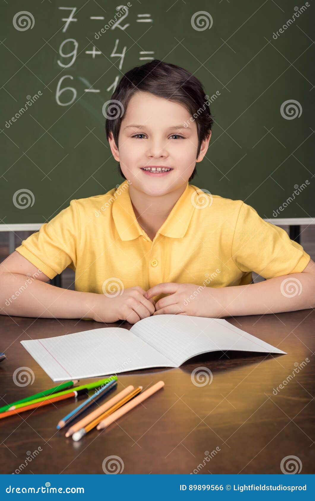 Smiling Boy Sitting at Table in Classroom Stock Photo - Image of books ...