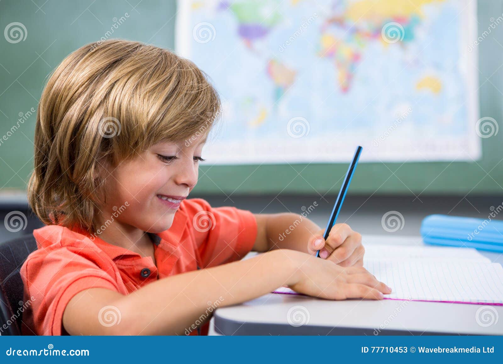 Smiling Boy Writing on Book in Classroom Stock Image - Image of ...