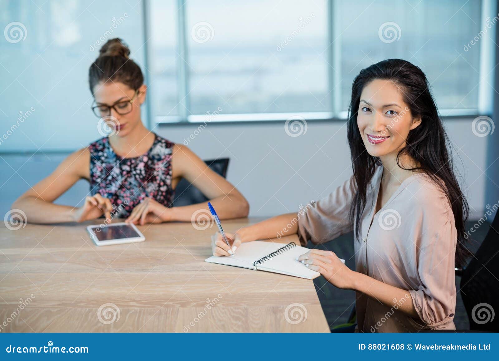 Smiling Business Colleagues Writing on Notepad and Using Digital Tablet ...