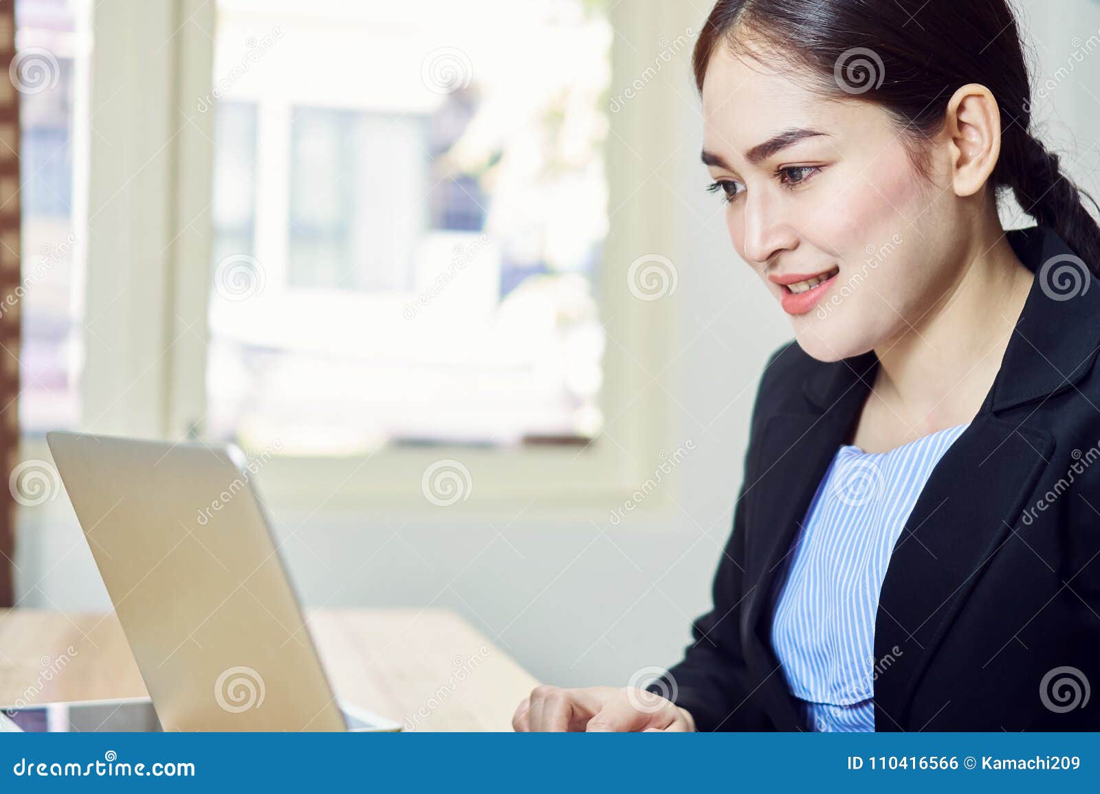 Smiling Business Woman in Black Suit is Sitting Working on Laptop in ... Smiling Business Woman in Black Suit is Sitting Working on Laptop in ...