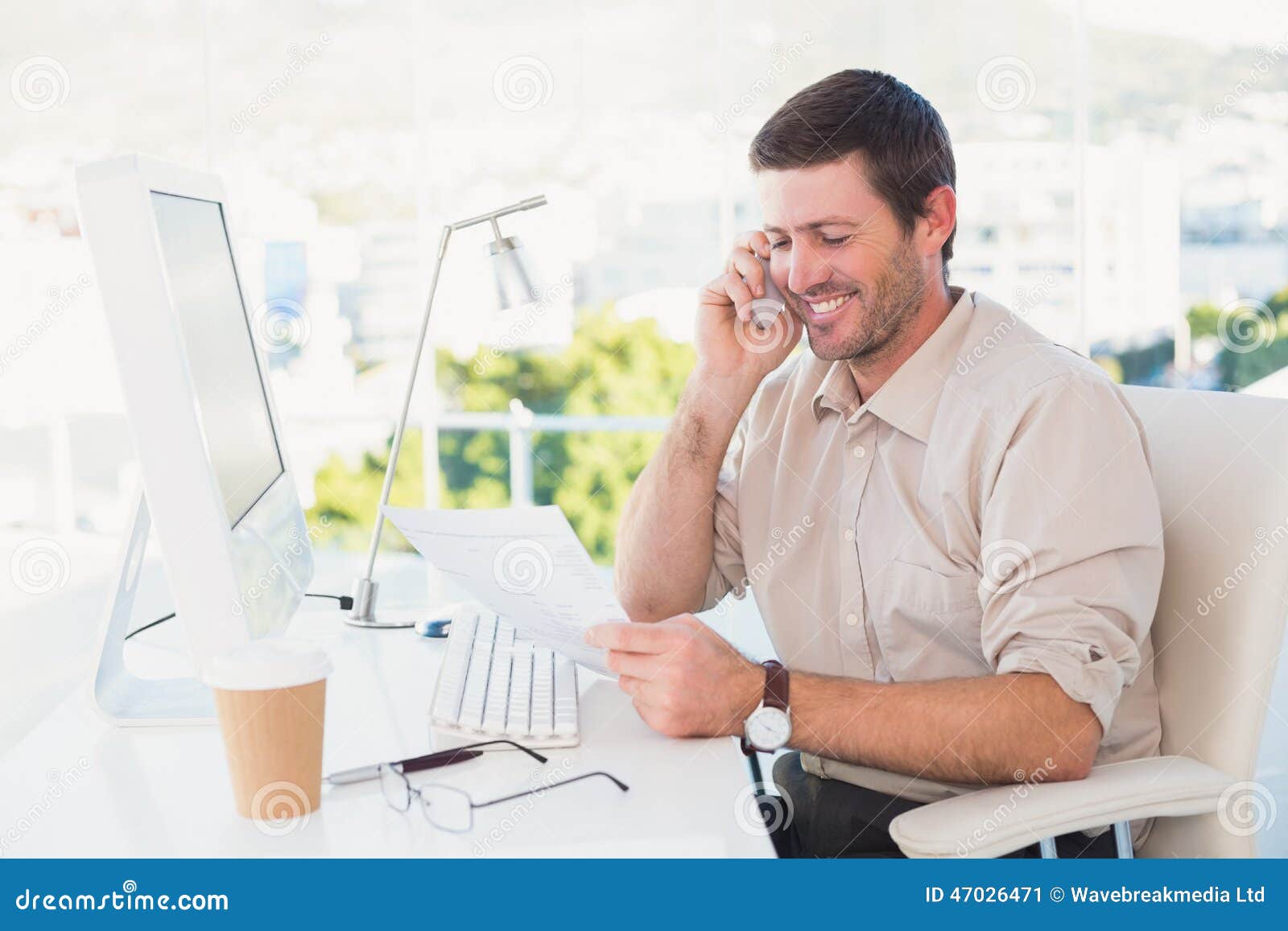 Smiling Businessman Making a Call and Reading a Document Stock Image ...