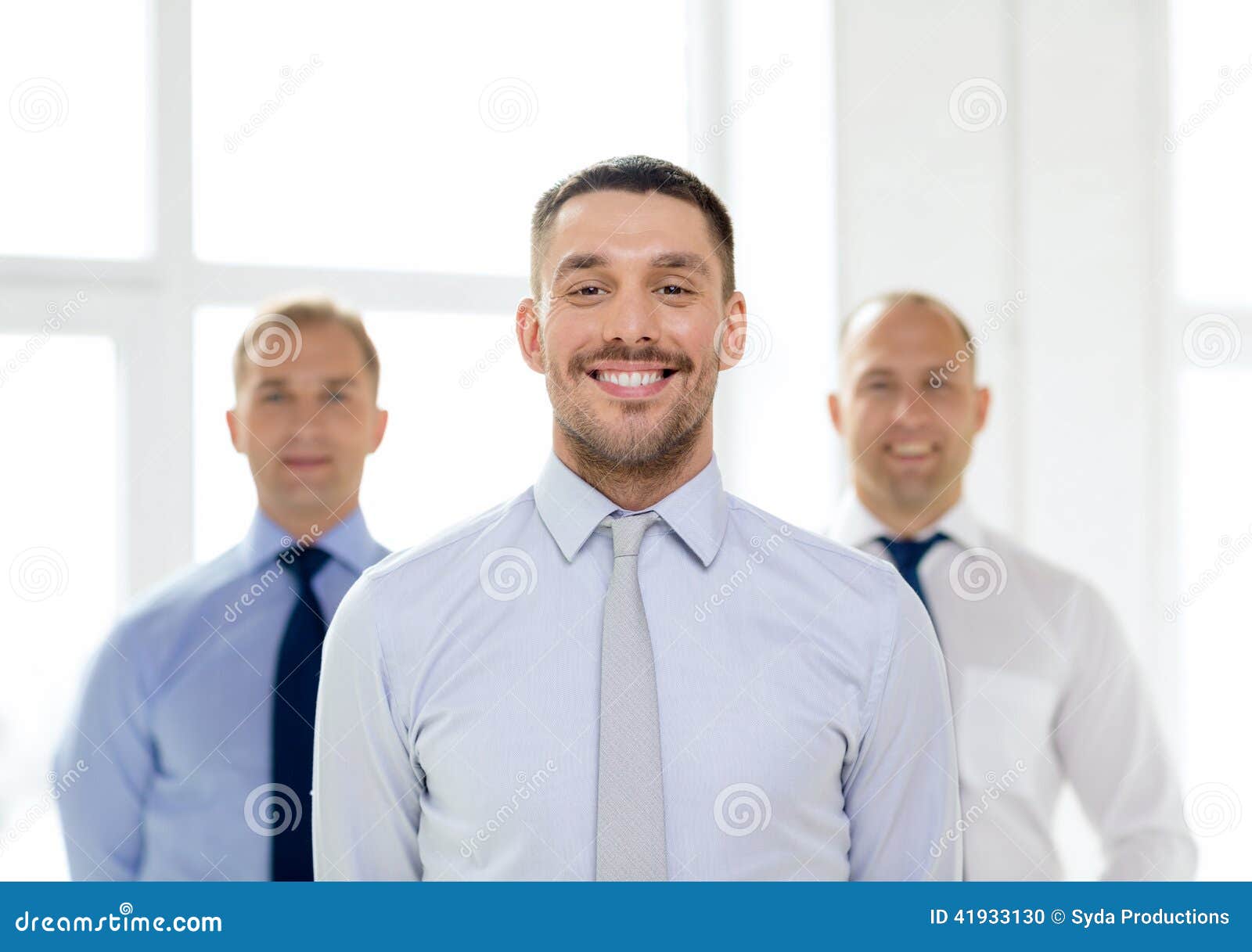 Smiling Businessman in Office with Team on Back Stock Photo - Image of ...