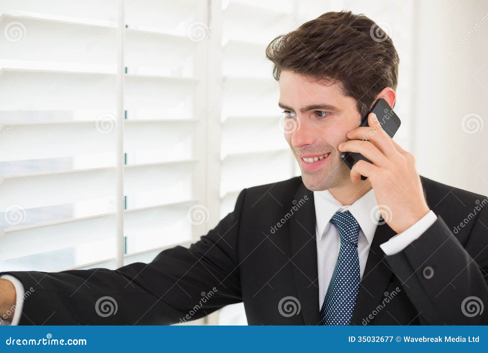 Smiling Businessman Peeking through Blinds while on Call Stock Image ...