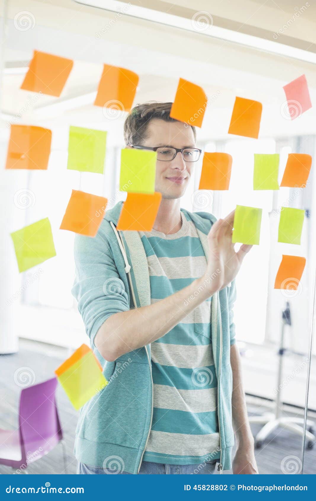 Smiling Businessman Reading Sticky Notes on Glass Wall in Creative ...