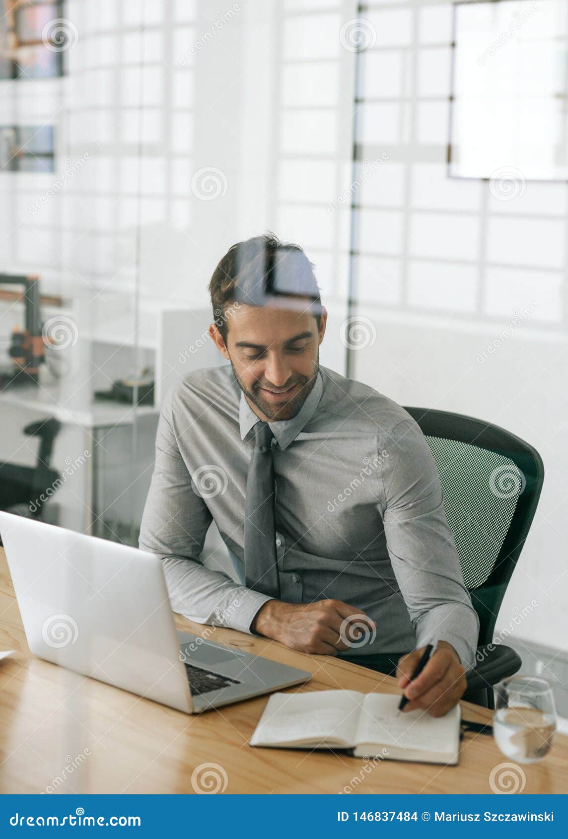 Smiling Businessman Sitting at Work Writing Ideas in a Notebook Stock ...