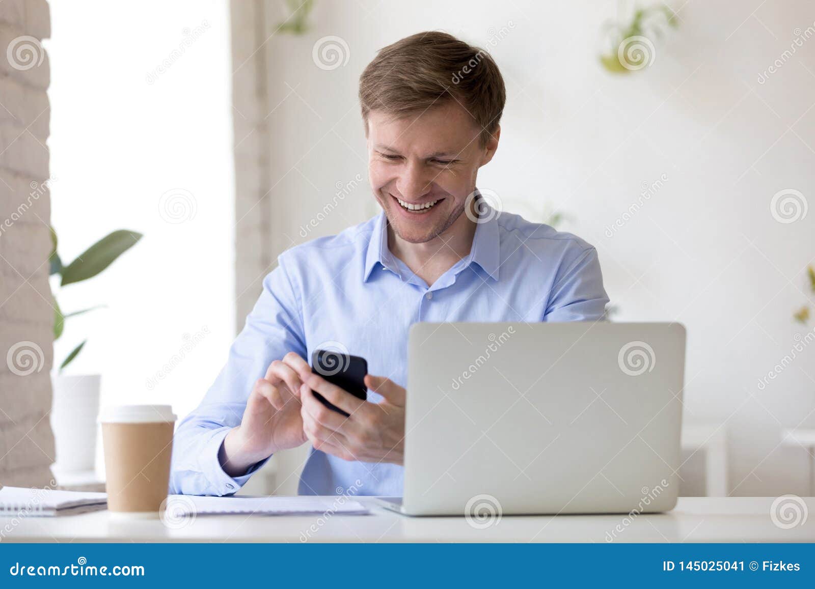 Smiling Businessman Using Cellphone and Laptop Computer at Modern ...