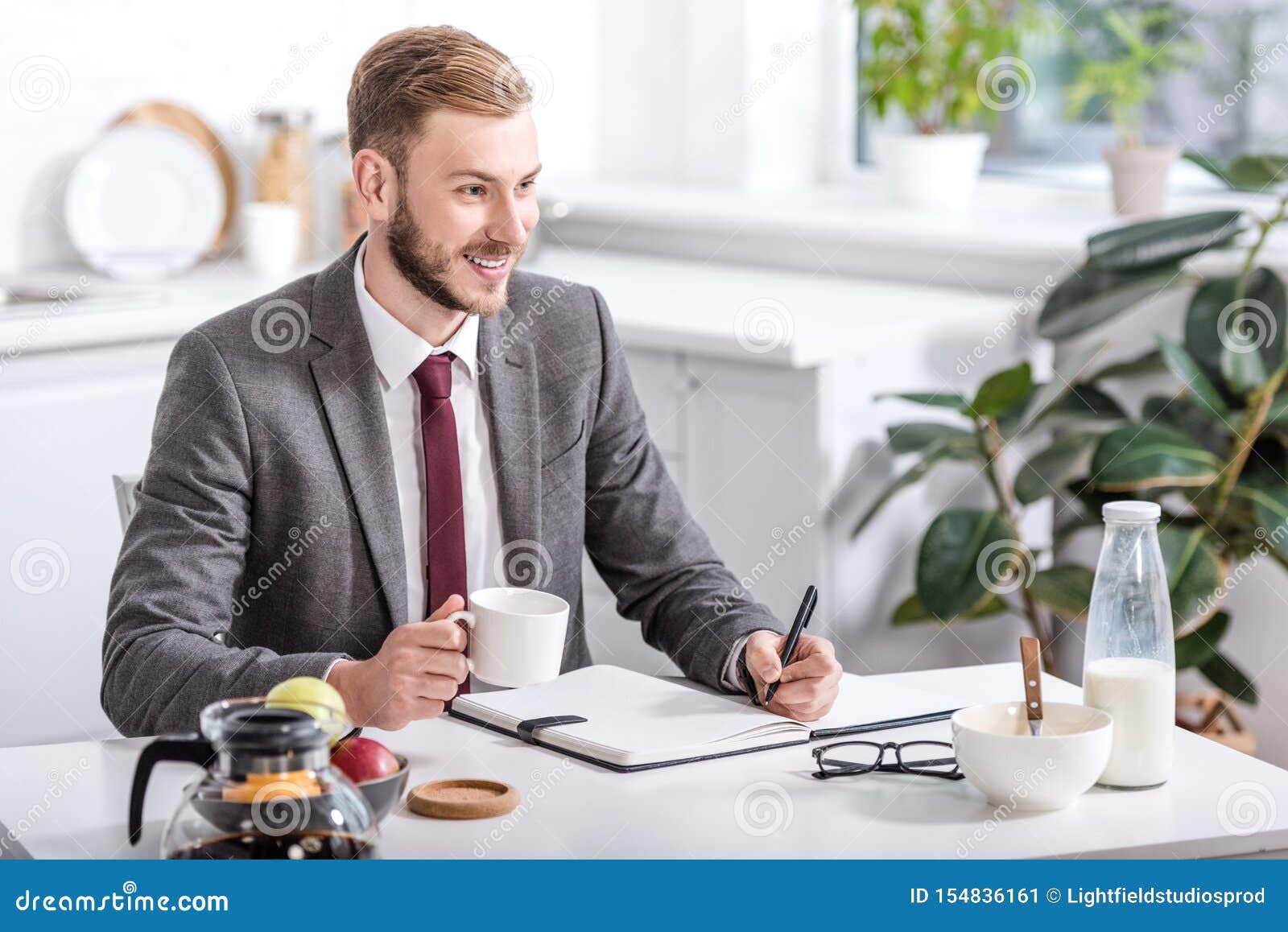 Smiling Businessman Writing in Notebook while Drinking Coffee and ...