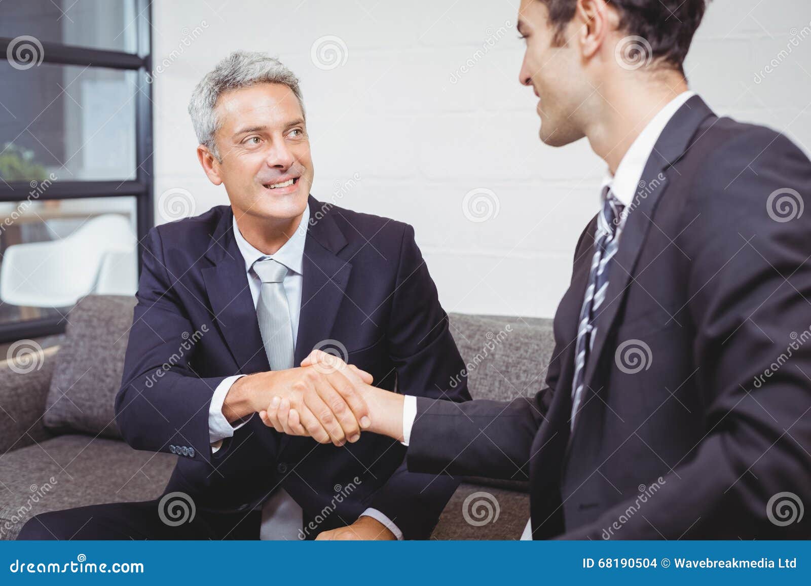 Smiling Businessmen Handshaking Stock Photo - Image of sitting, indoors ...