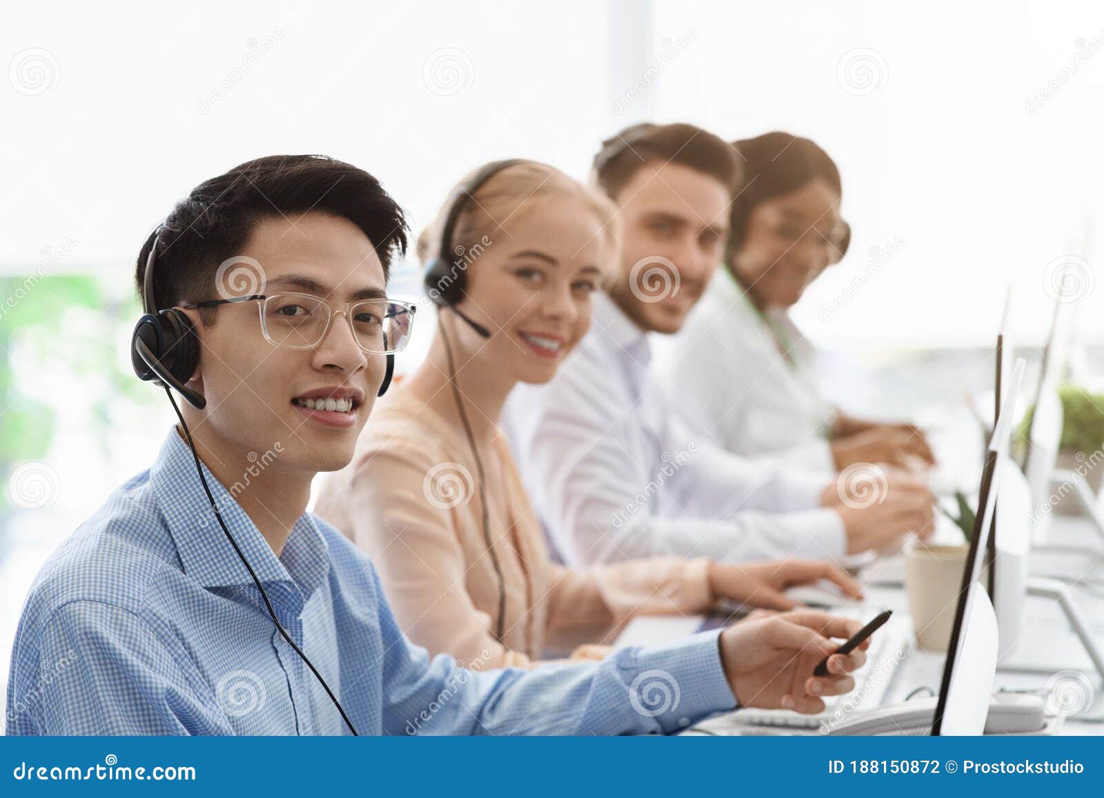 Smiling Call Center Workers Sitting in Row Near Their Computers at ...