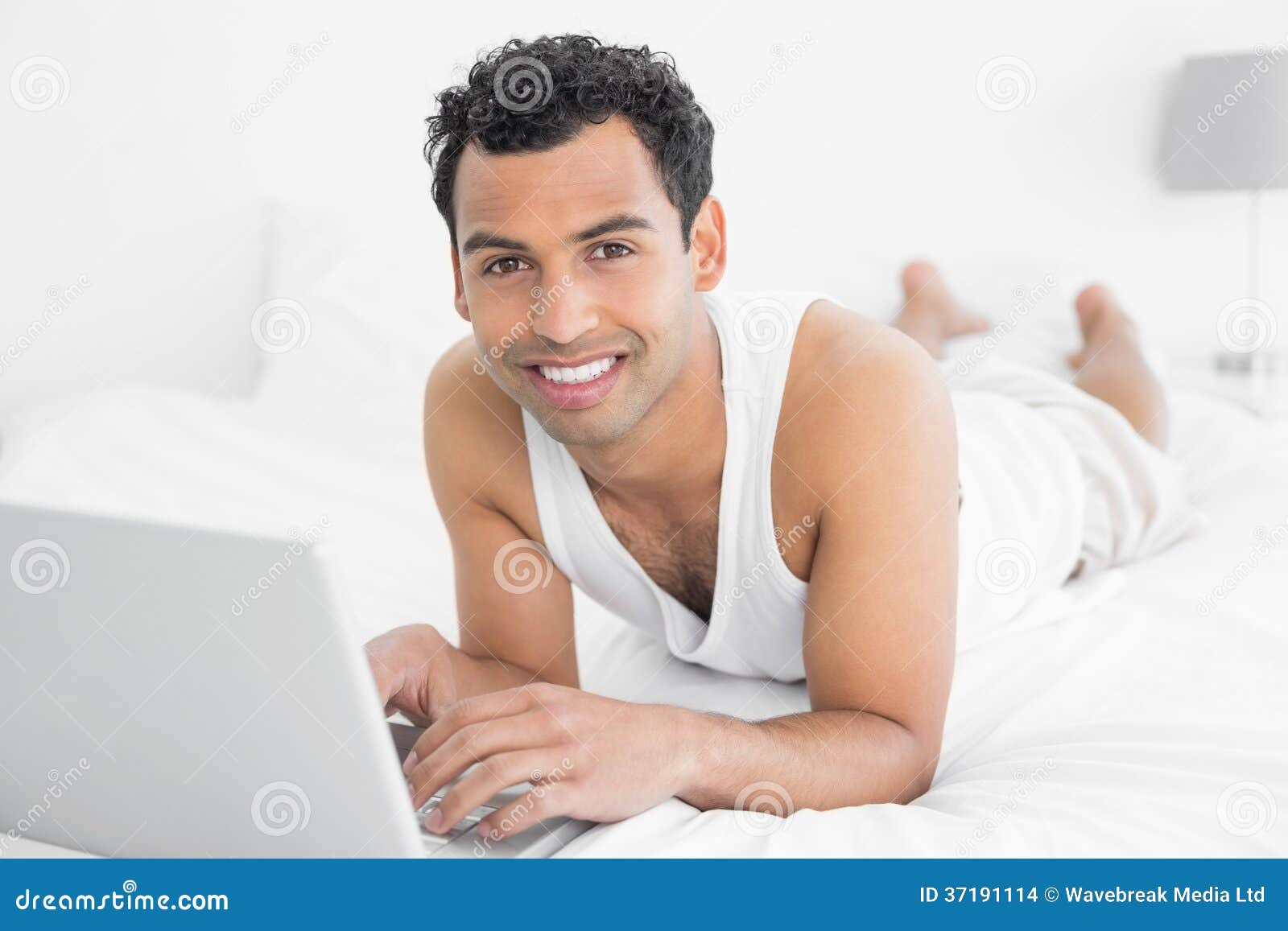 Smiling Casual Young Man Using Laptop in Bed Stock Photo - Image of ...