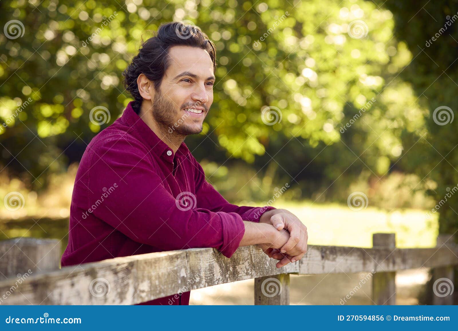 Smiling Casually Dressed Mature Man Leaning On Fence On Walk In