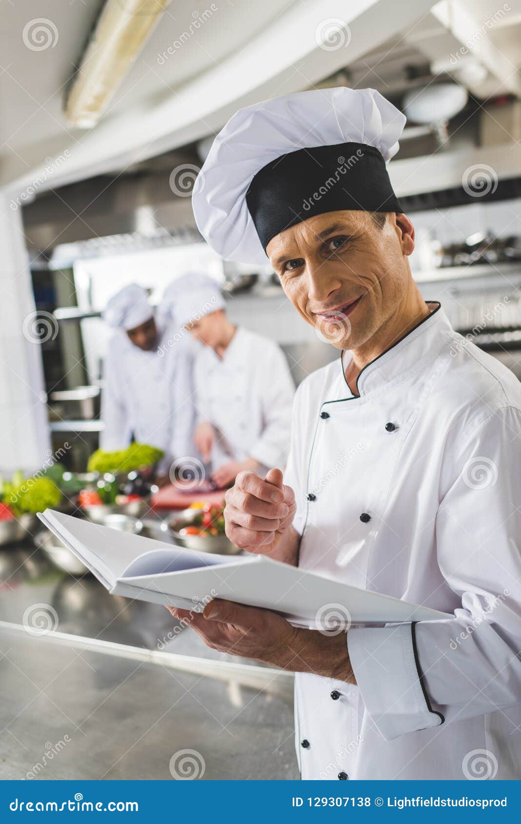 Smiling Chef Holding Recipe Book and Looking at Camera Stock Photo ...