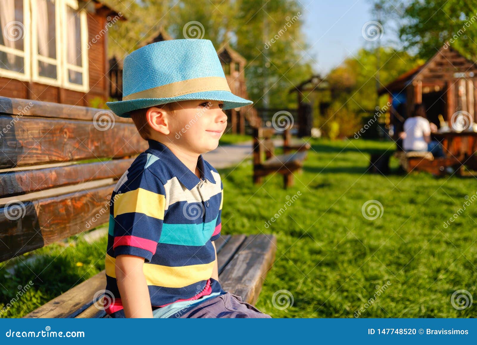 Smiling Child Sitting on a Park Bench with Green Meadow on Background ...