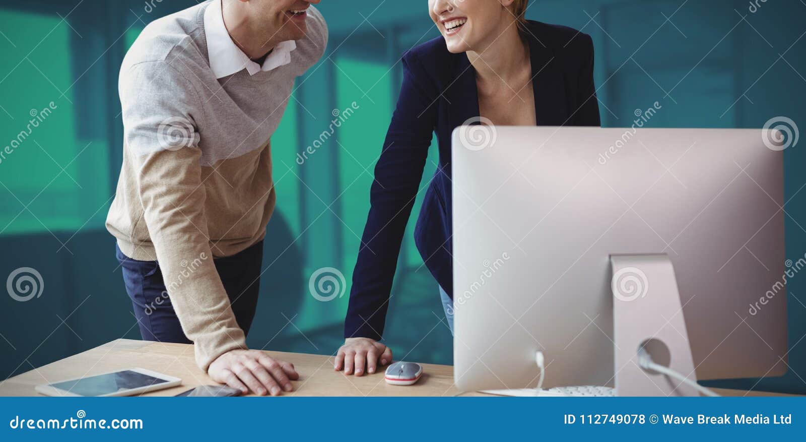 Composite Image of Smiling Colleagues Discussing Over Computer at Table ...