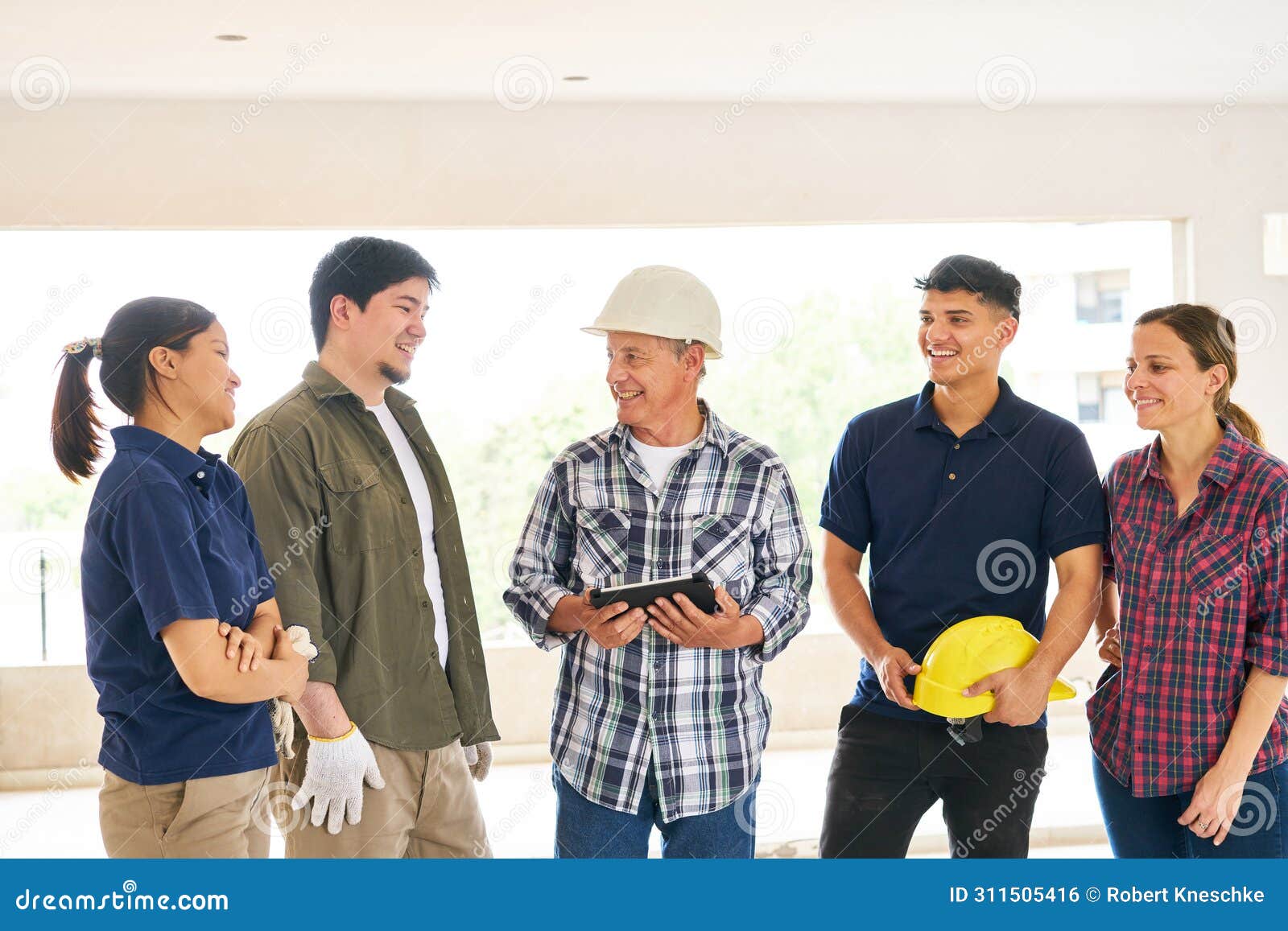 Smiling Contractor Holding Tablet PC Discussing with Construction Team ...