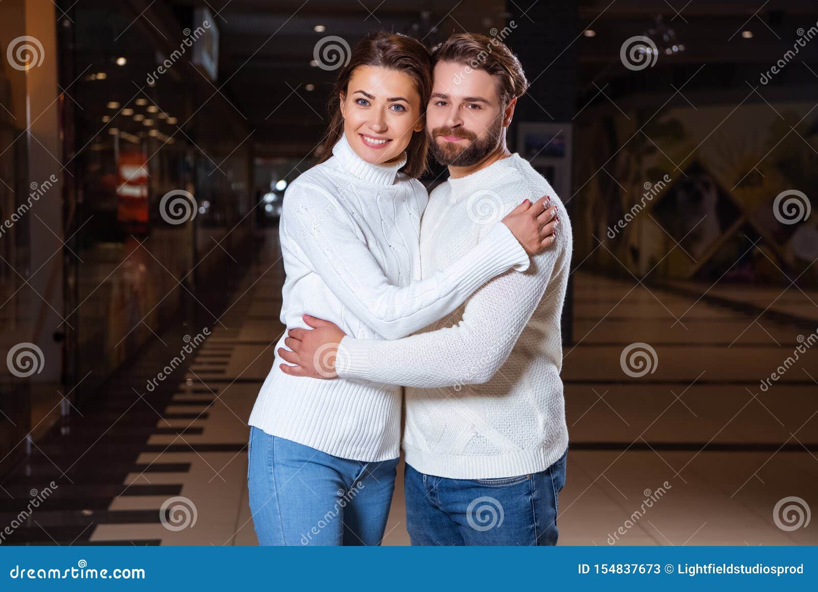 Smiling Couple in White Sweaters Hugging and Looking Stock Image ...