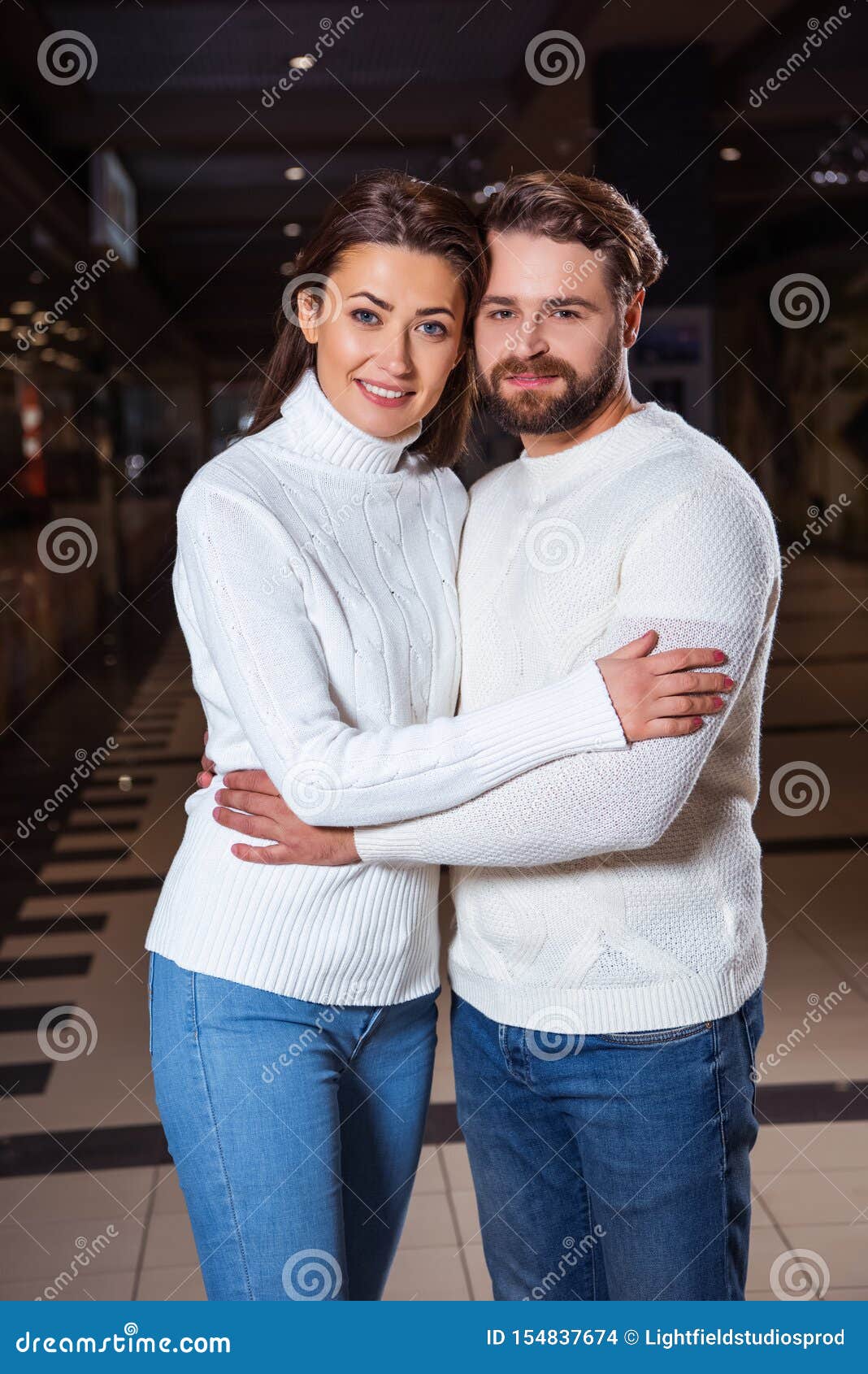 Smiling Couple in White Sweaters Hugging and Looking Stock Photo ...