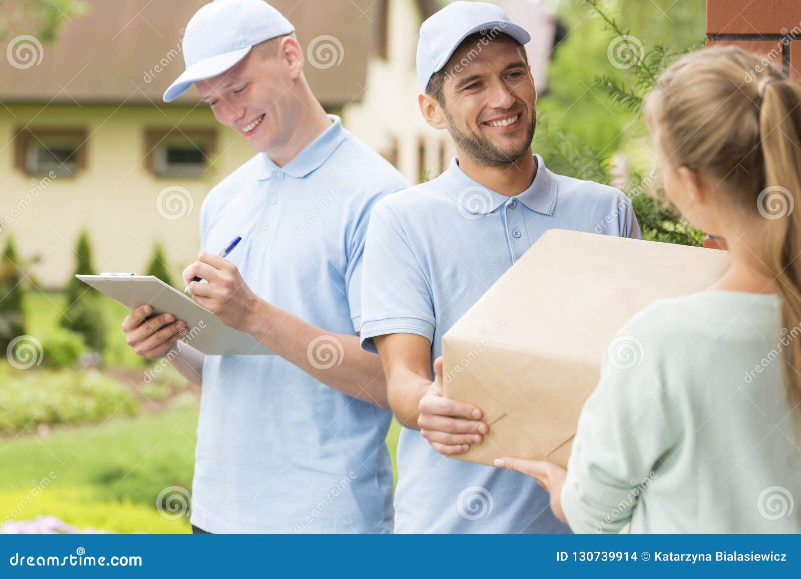 Friendly Couriers In Blue Uniforms And Woman Signing Receipt Of Package ...