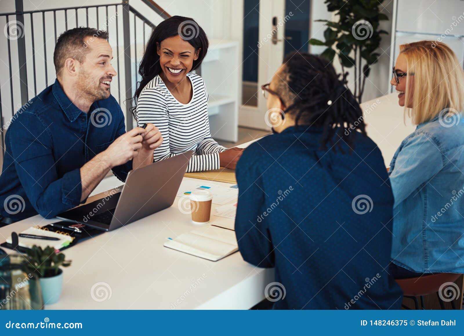 Smiling Coworkers Talking Together At A Table In An Office Stock Image