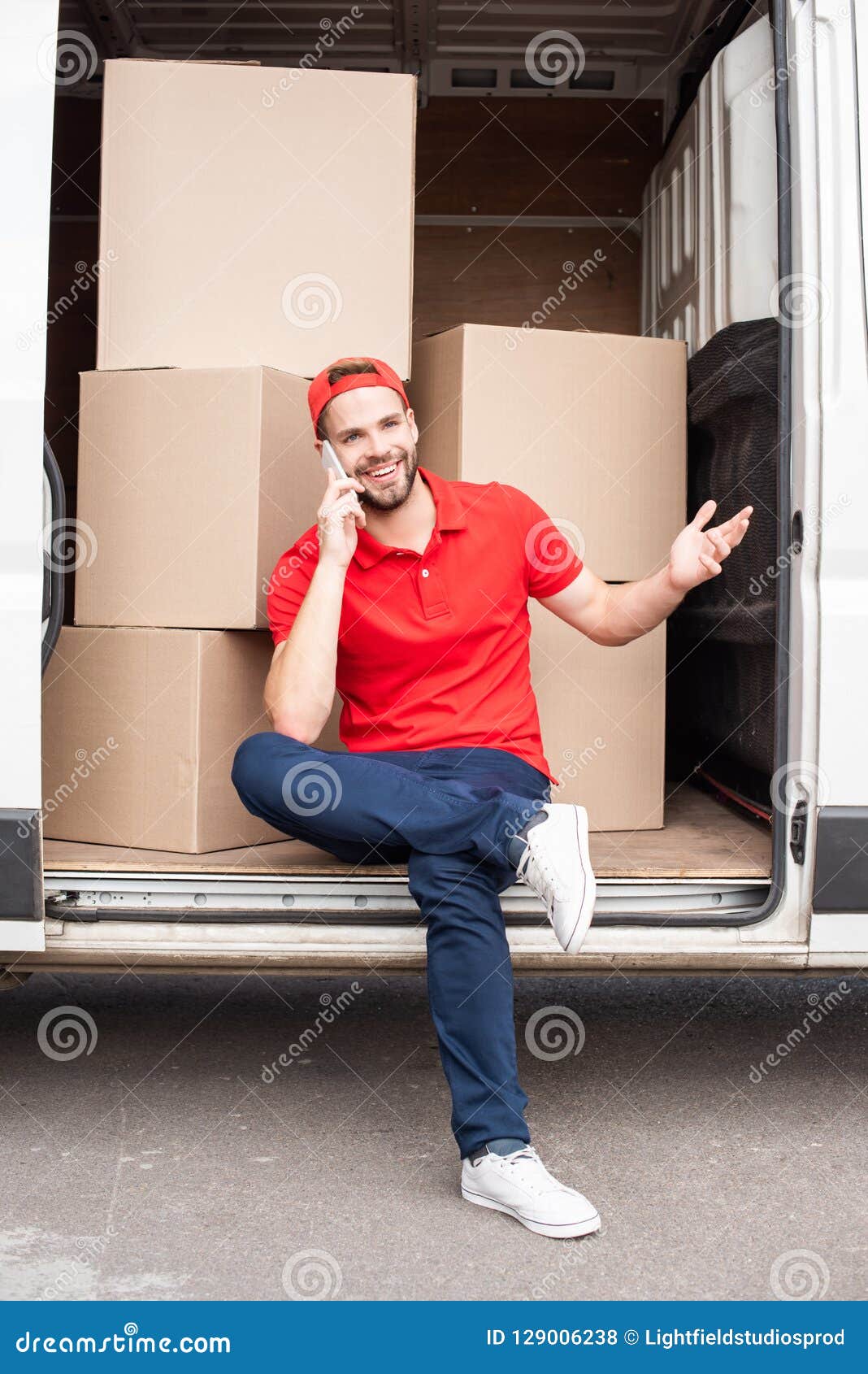 Smiling Delivery Man in Red Uniform Talking on Smartphone while Resting ...