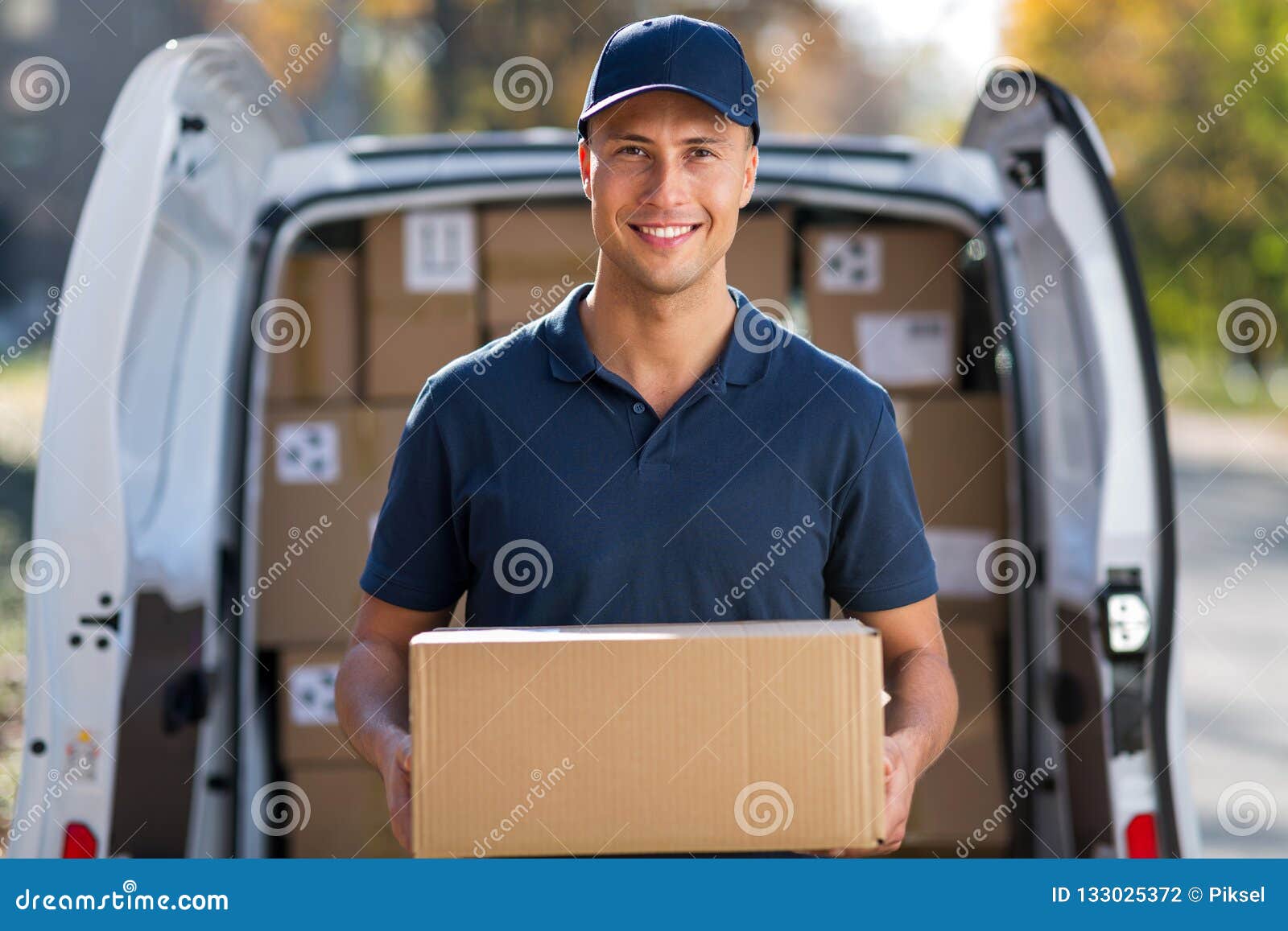 Smiling Delivery Man Standing in Front of His Van Holding a Package ...