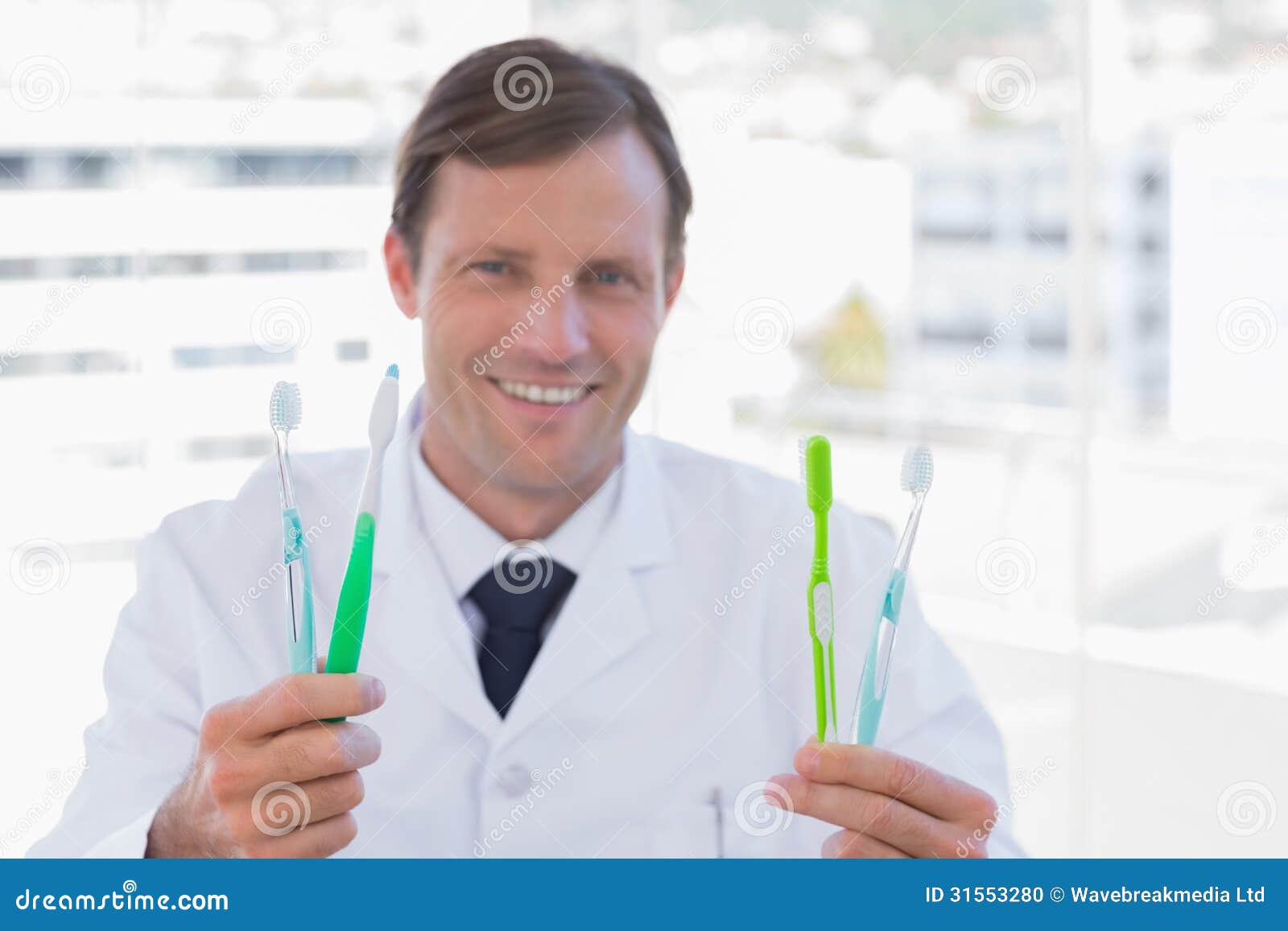 Smiling Doctor Holding Two Toothbrushes Stock Photo - Image of indoors ...