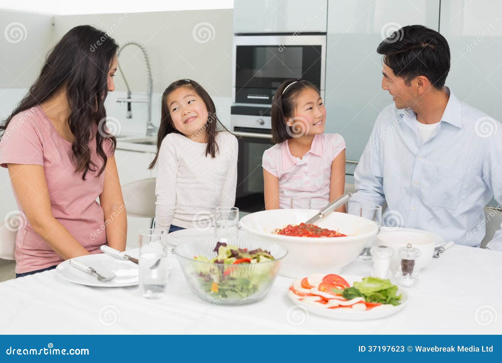 Smiling Family of Four Sitting at Dining Table in Kitchen Stock Image ...