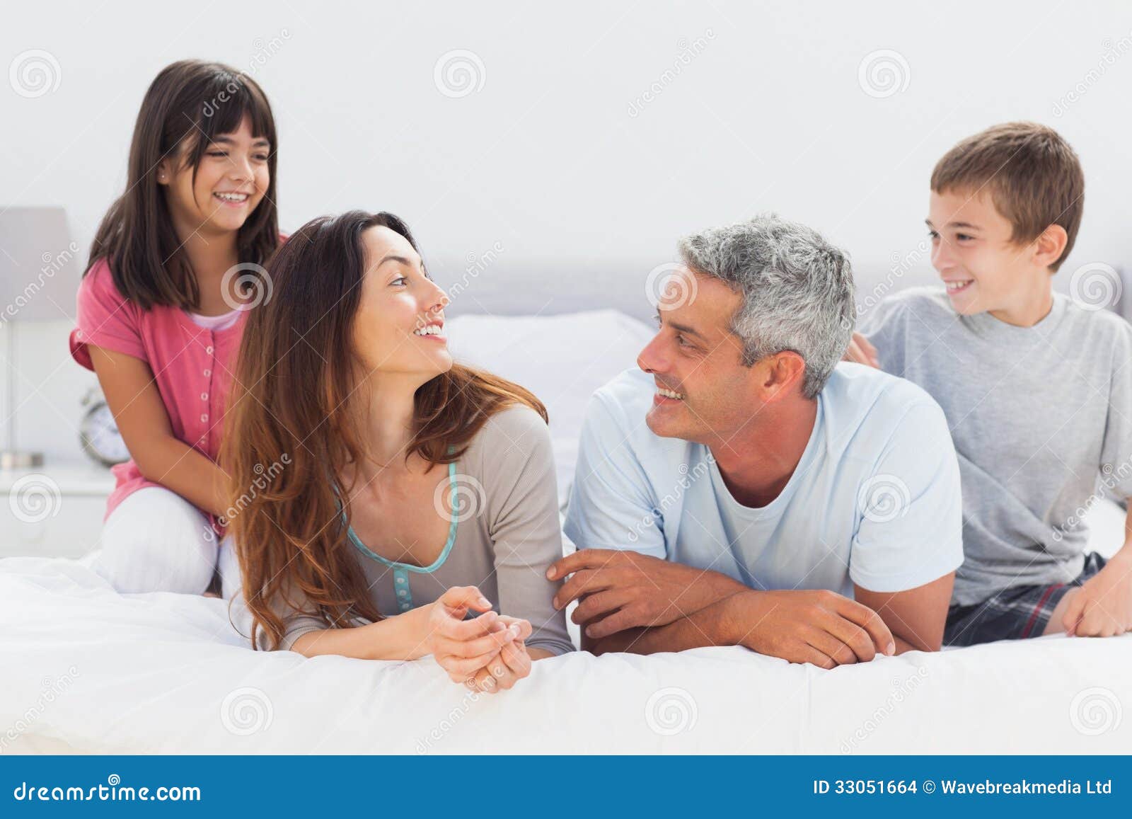Smiling Family Talking Together on Bed Stock Photo - Image of smiling ...