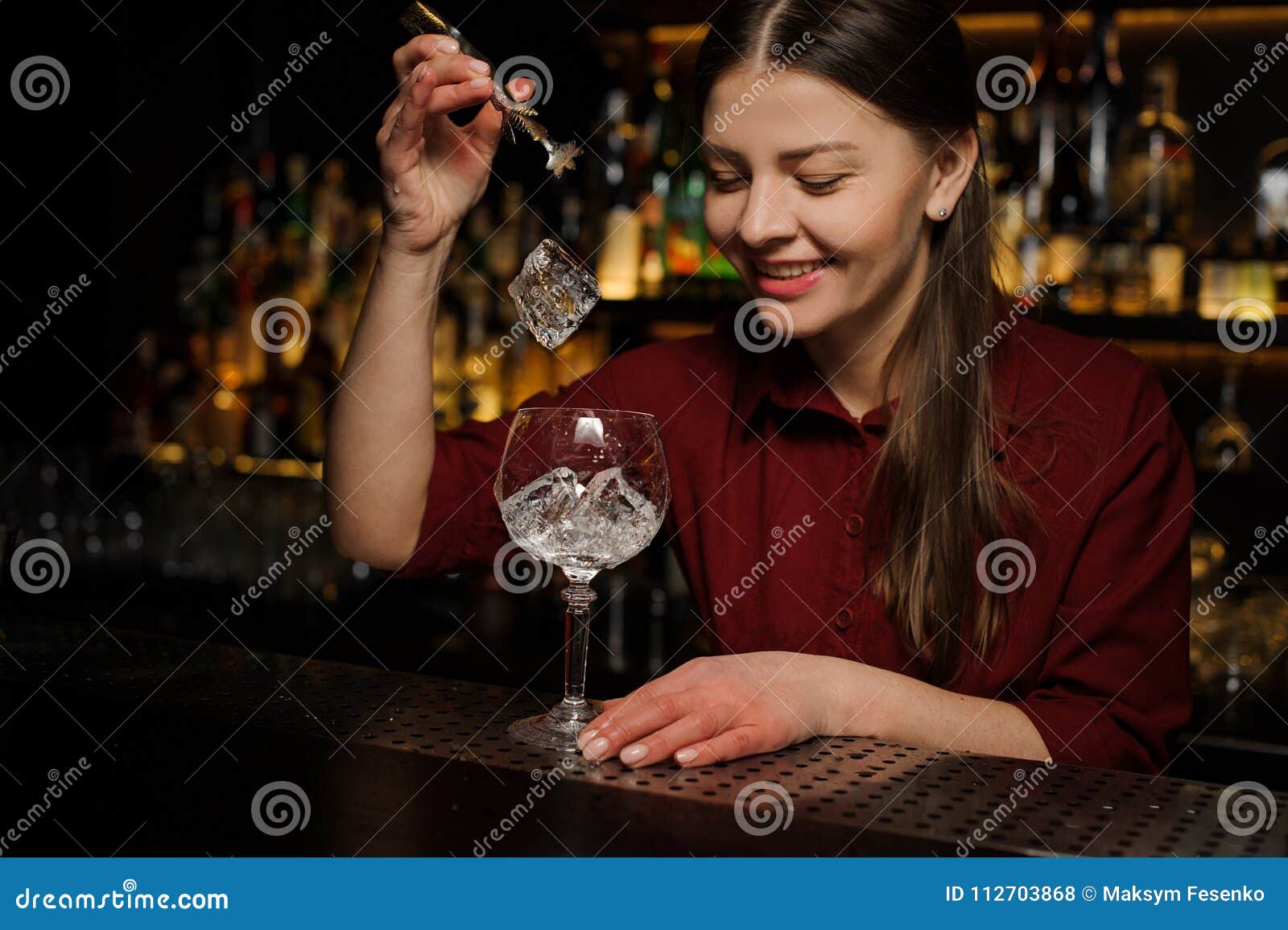 Smiling Female Barman Putting Ice Cubes Into A Glass Making An A Stock