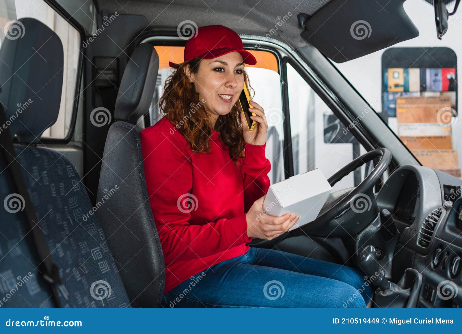 Smiling Female Delivery Driver Calling Someone about Their Pack Stock ...