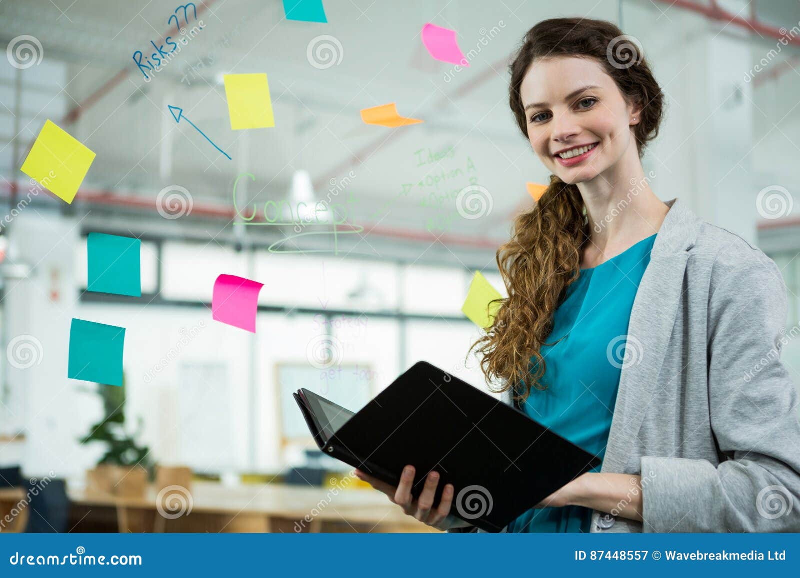 Smiling Female Executive Standing with Folder in Creative Office Stock ...