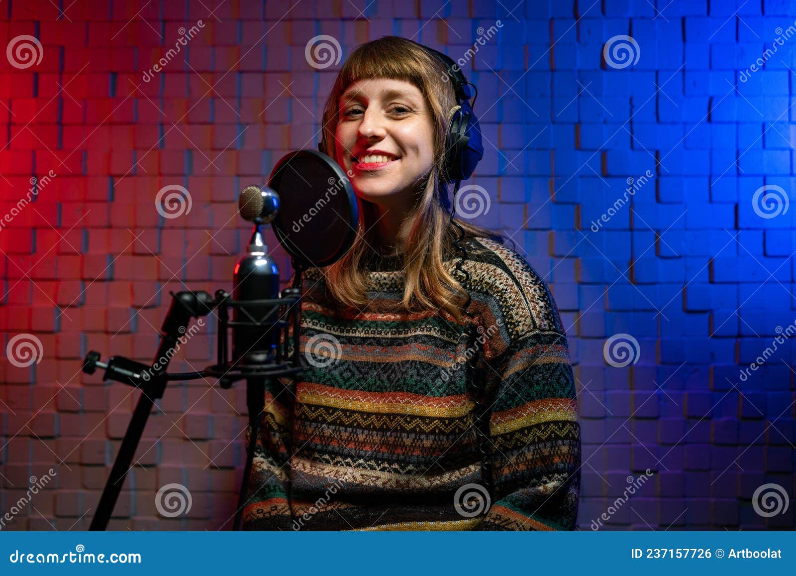 A Smiling Friendly Singer in Headphones Poses for Camera at Microphone ...