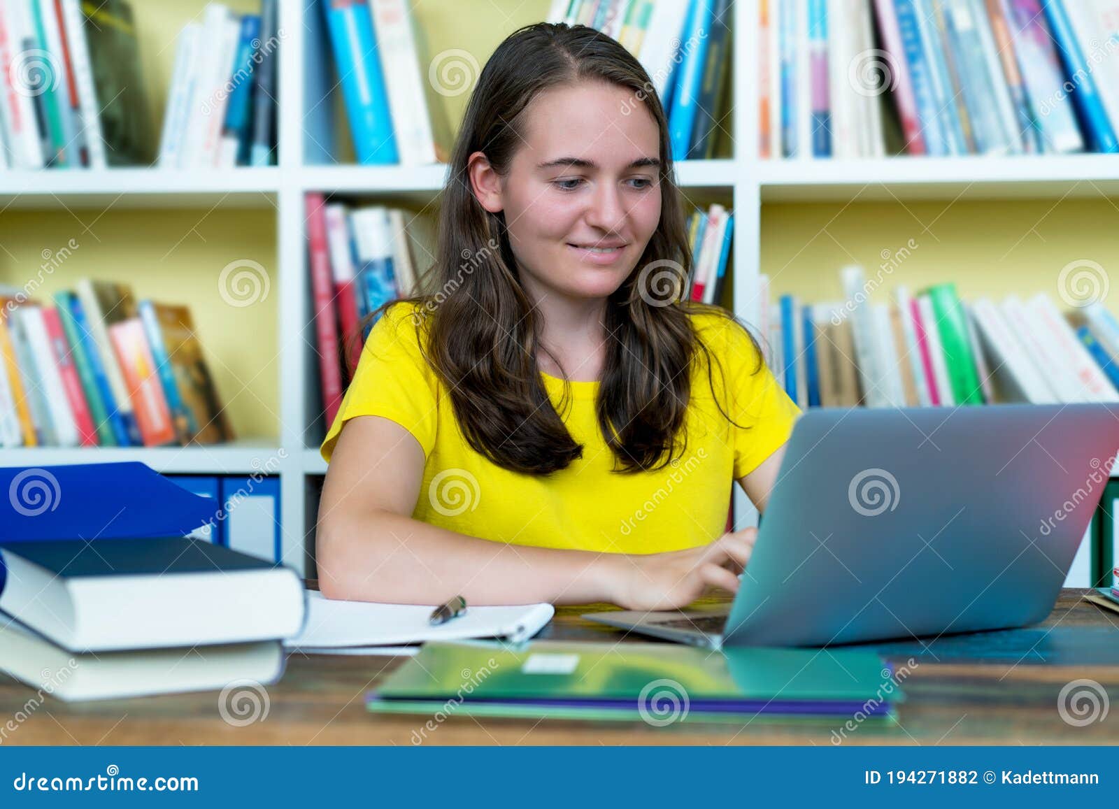 Smiling German Female Student Learning with Book and Computer at Desk ...